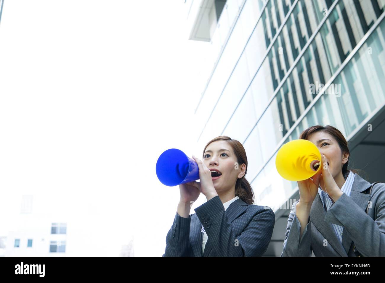 Two office workers shouting into a megaphone in an office building ...