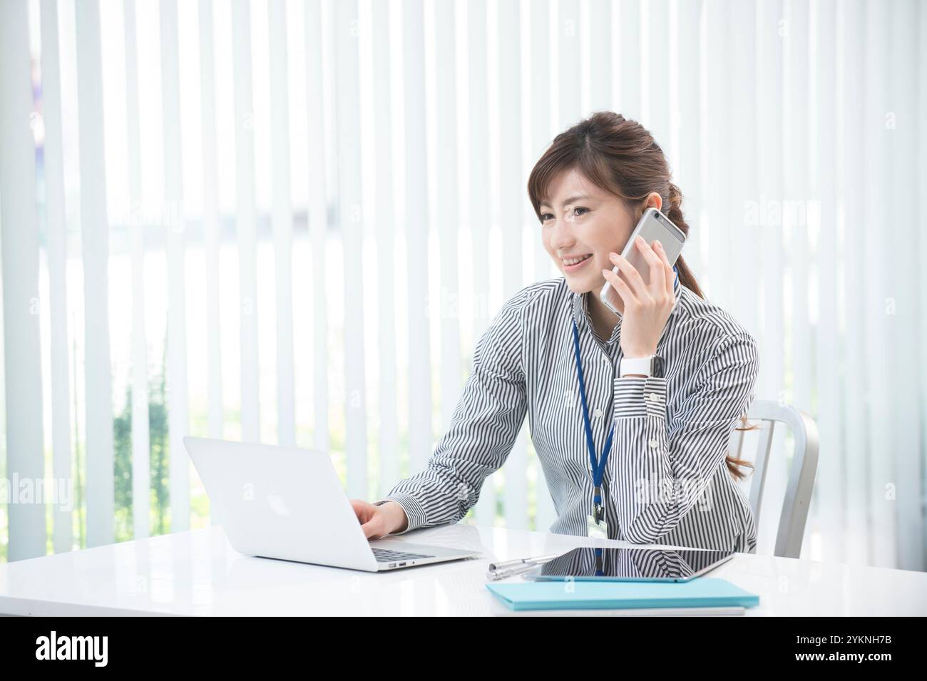 Office worker working at a desk at a PC while on the phone Stock Photo ...