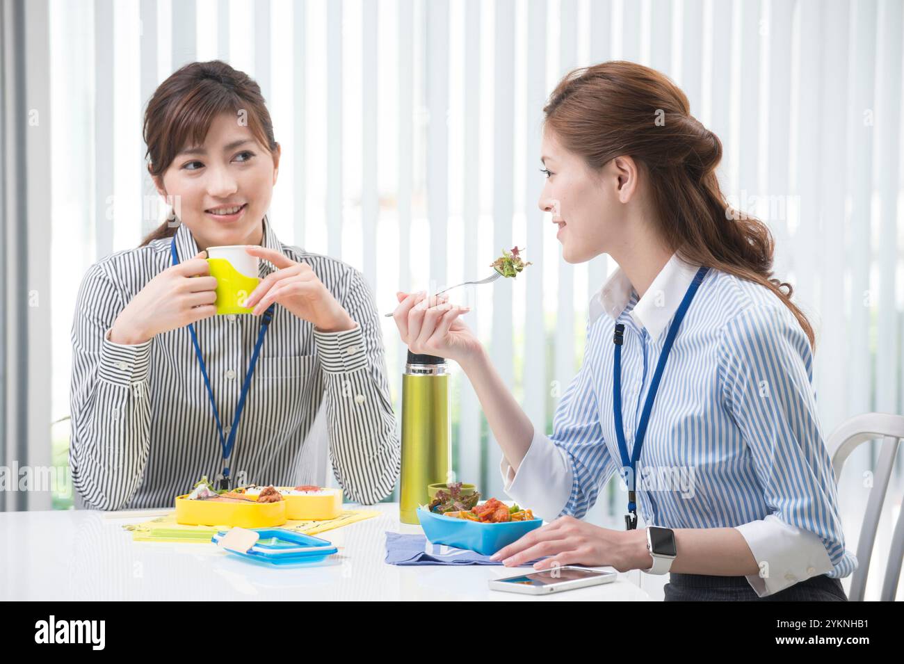 Two office workers eating lunch in office Stock Photo - Alamy