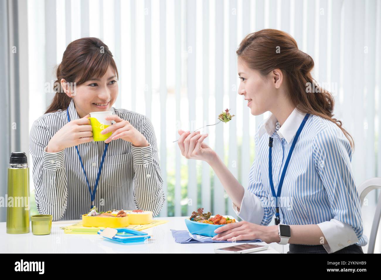 Two office workers eating lunch in office Stock Photo - Alamy