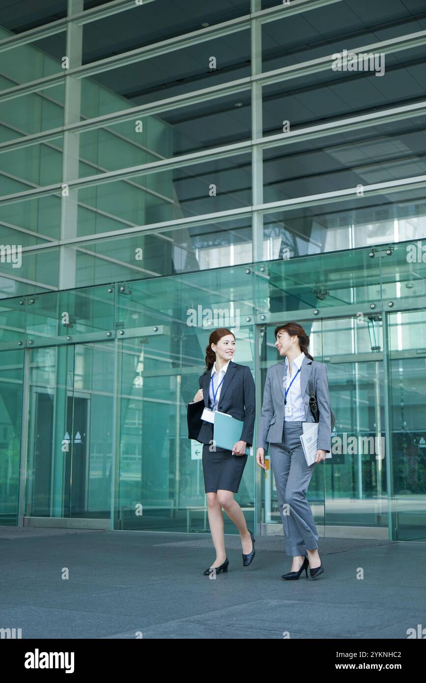 Two office workers walking through office building Stock Photo - Alamy