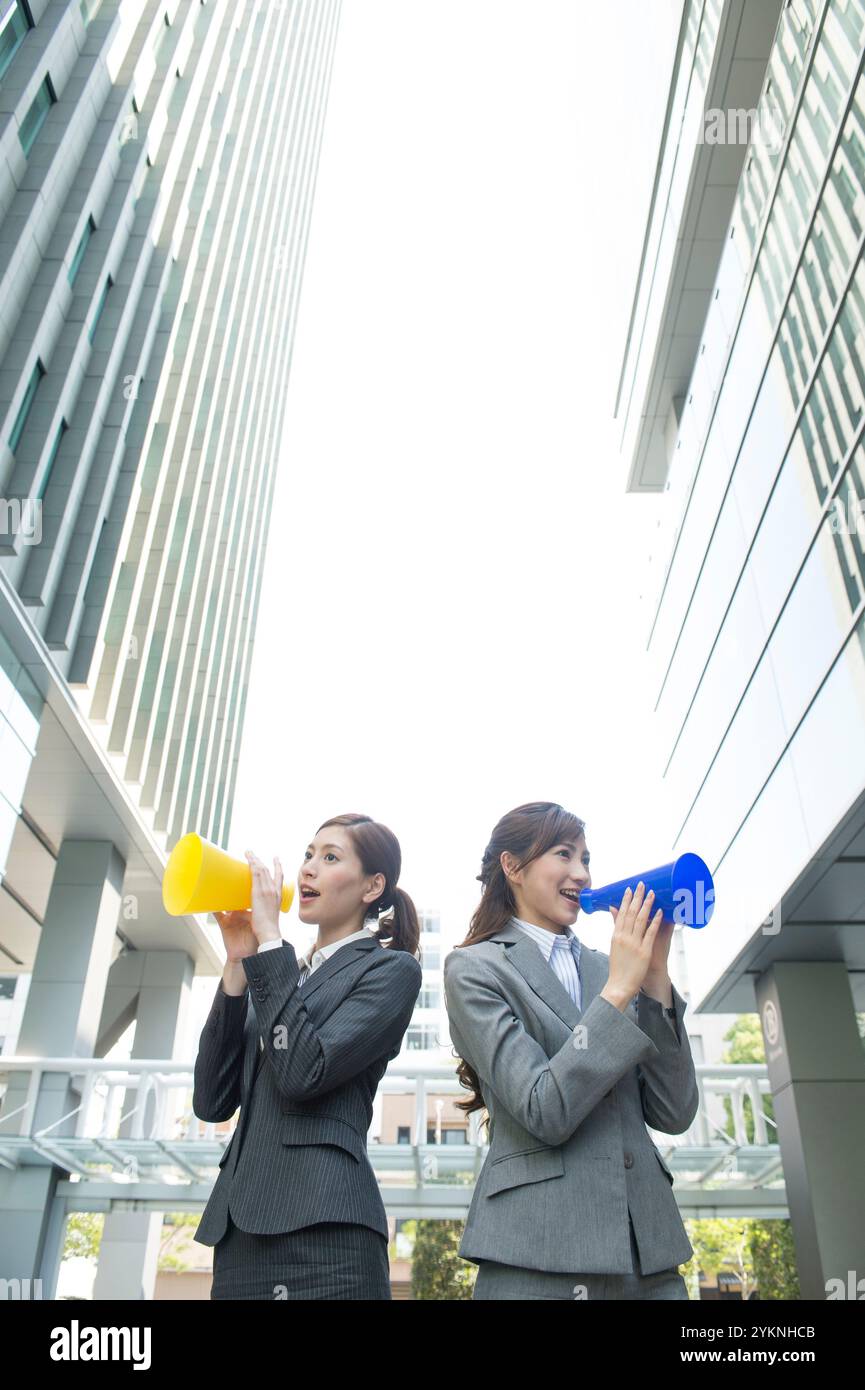 Two office workers shouting into a megaphone in an office building ...