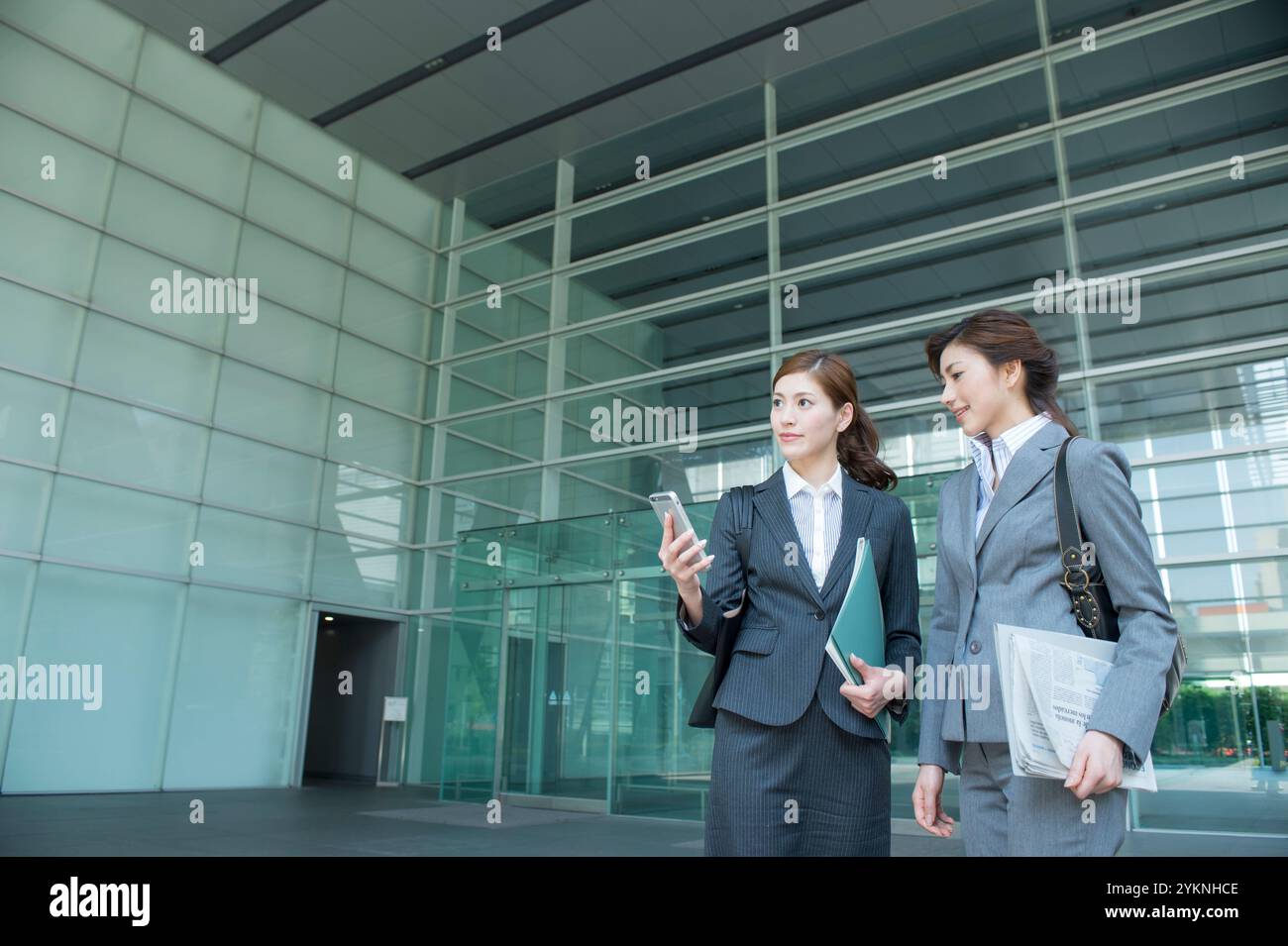 Two office workers looking at their phones in an office building Stock ...
