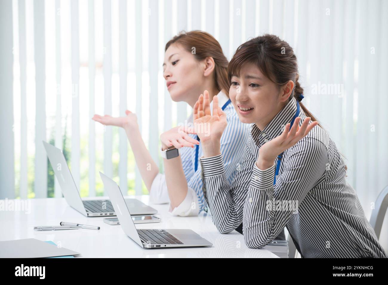 Two office workers at their desk at a computer playing omedama Stock ...