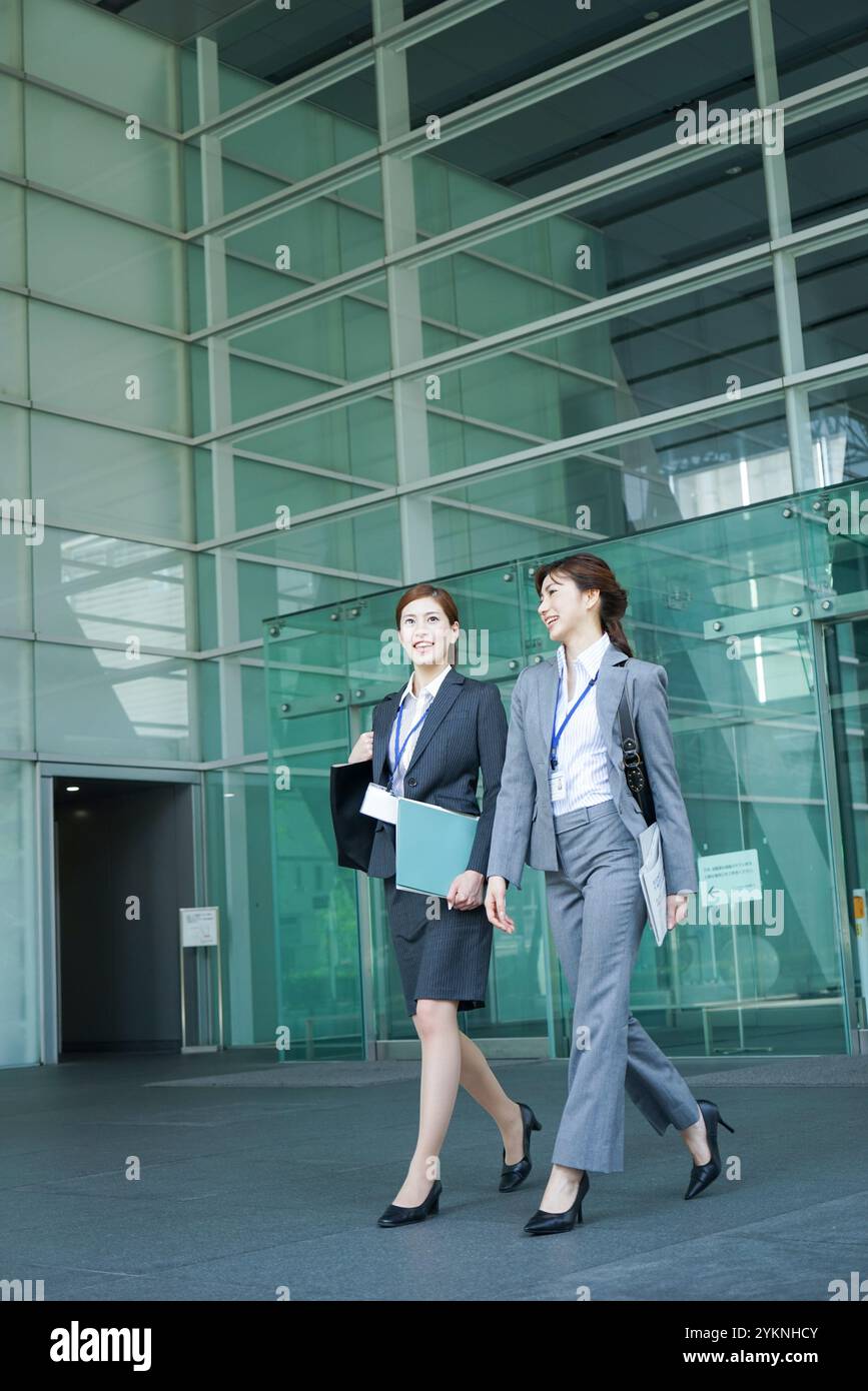 Two office workers walking through office building Stock Photo - Alamy