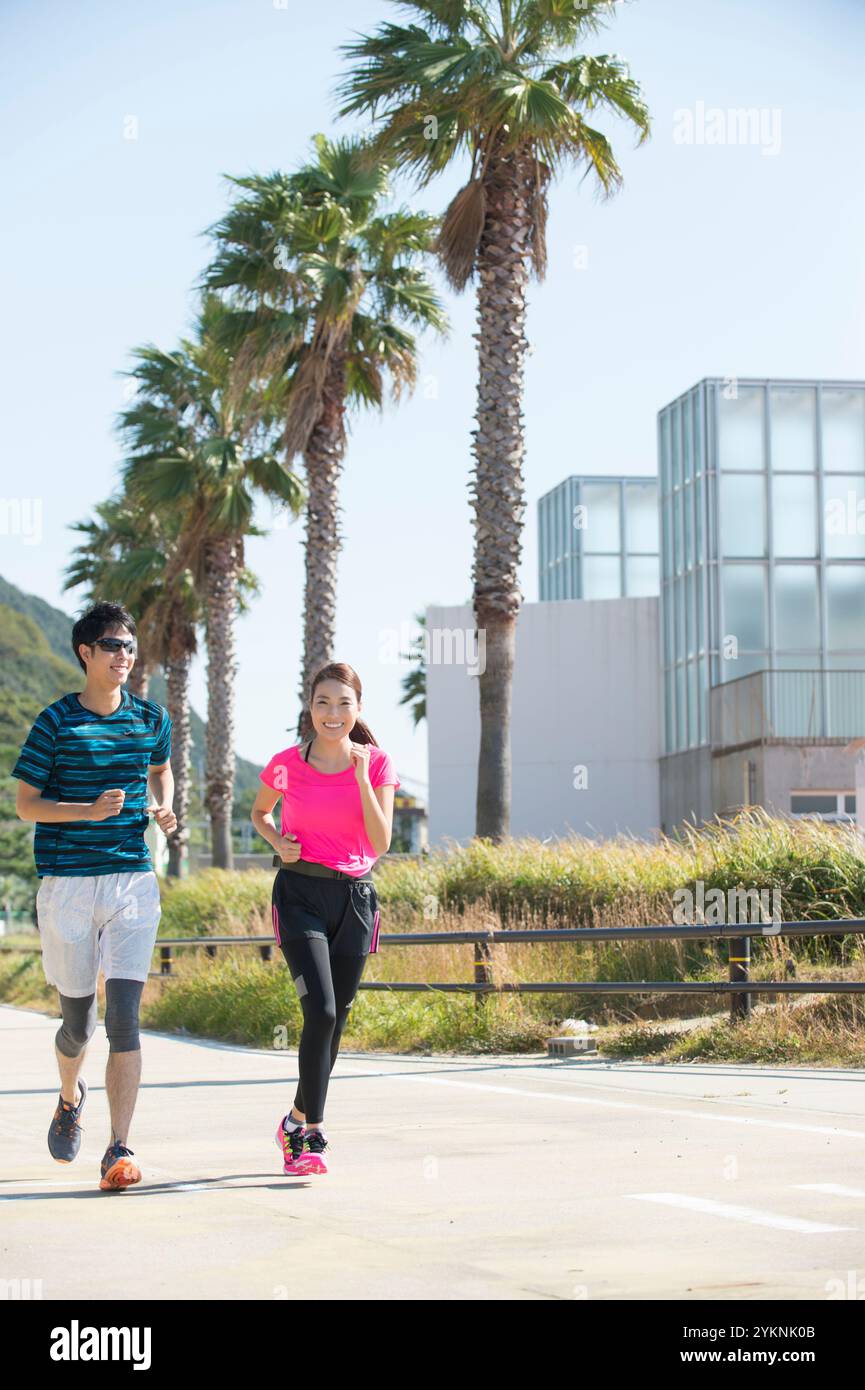 Couple running alongside palm trees Stock Photo - Alamy