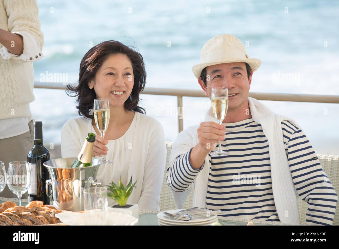 Middle-aged couple drinking champagne at a restaurant on the beach ...