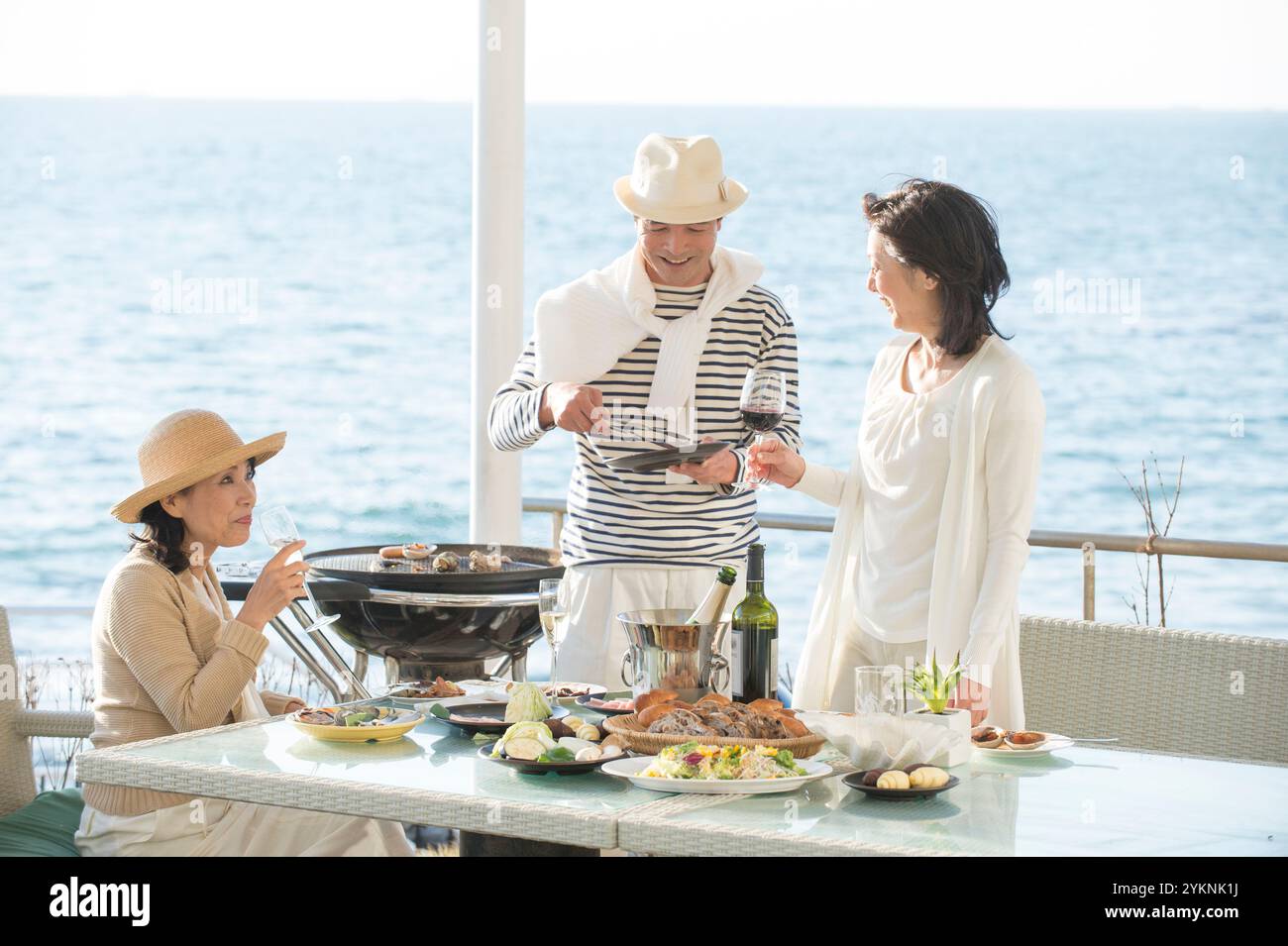 A group of middle-aged people barbecuing at a restaurant on the beach ...
