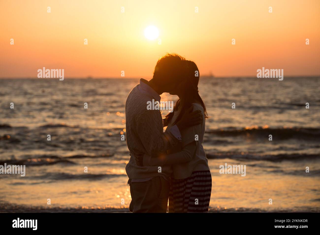 Couple kissing on the beach at sunset Stock Photo - Alamy