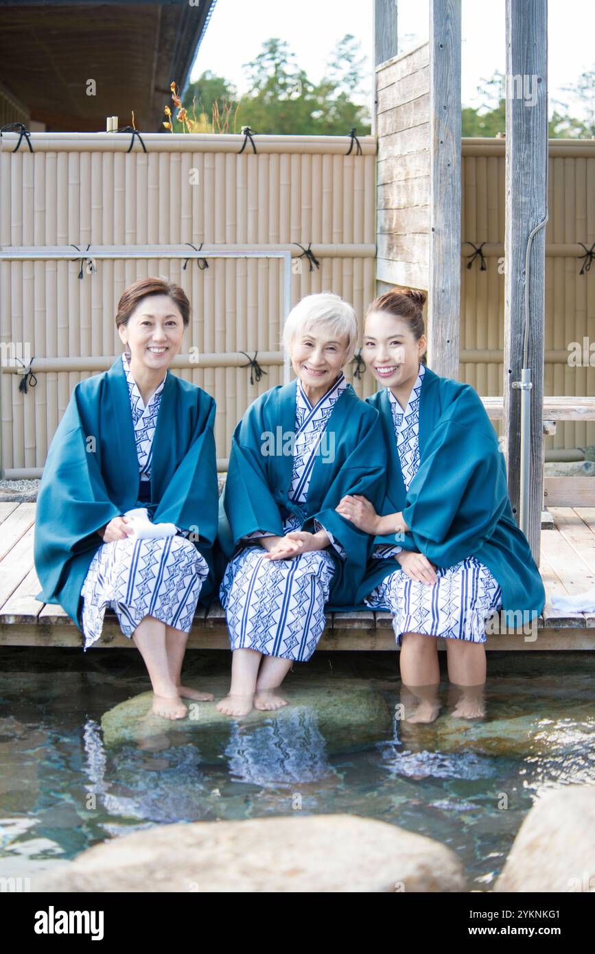 Mother, daughter and mother-in-law in yukata and haori bathing feet ...
