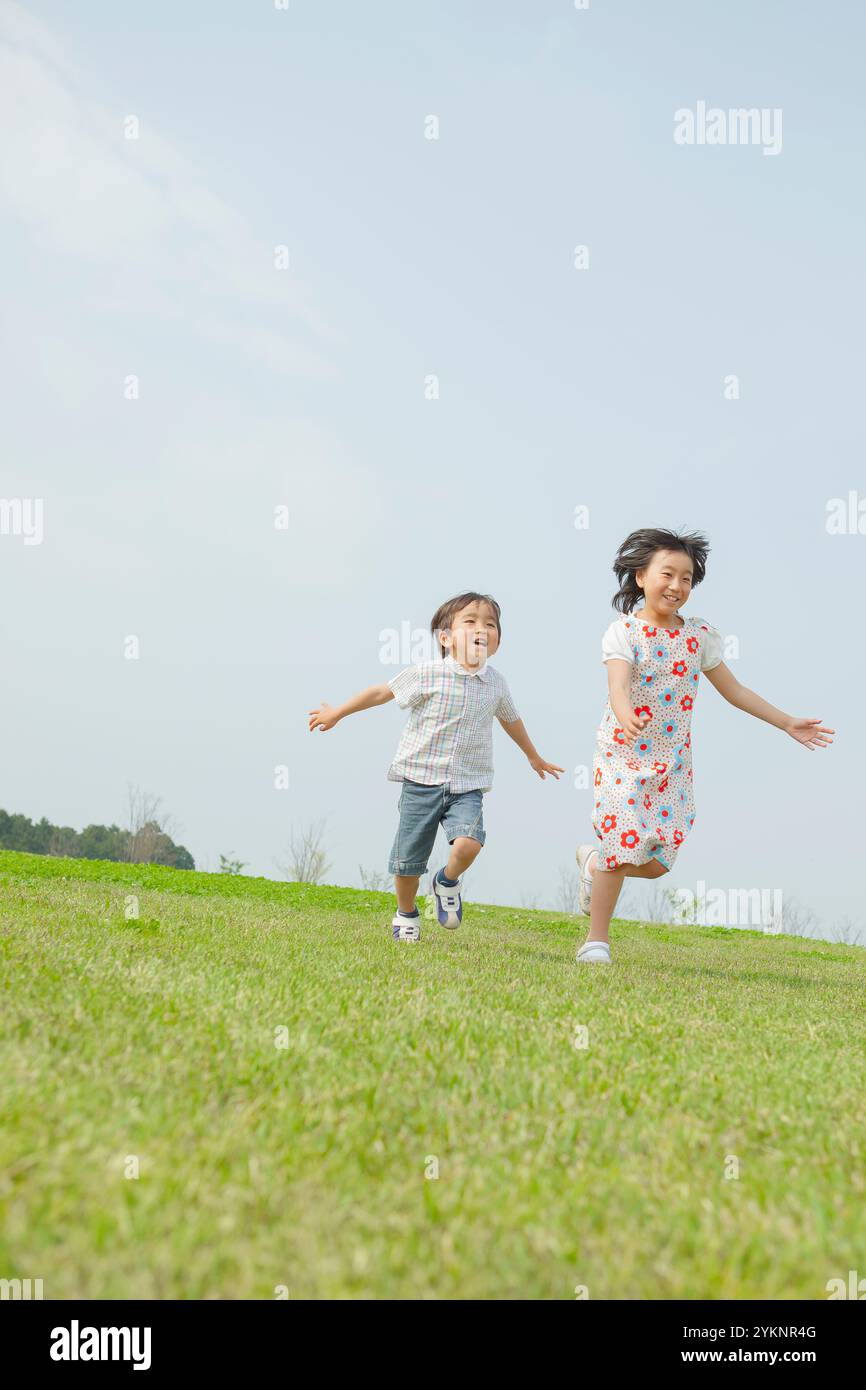 Sister and brother running in grassland Stock Photo - Alamy