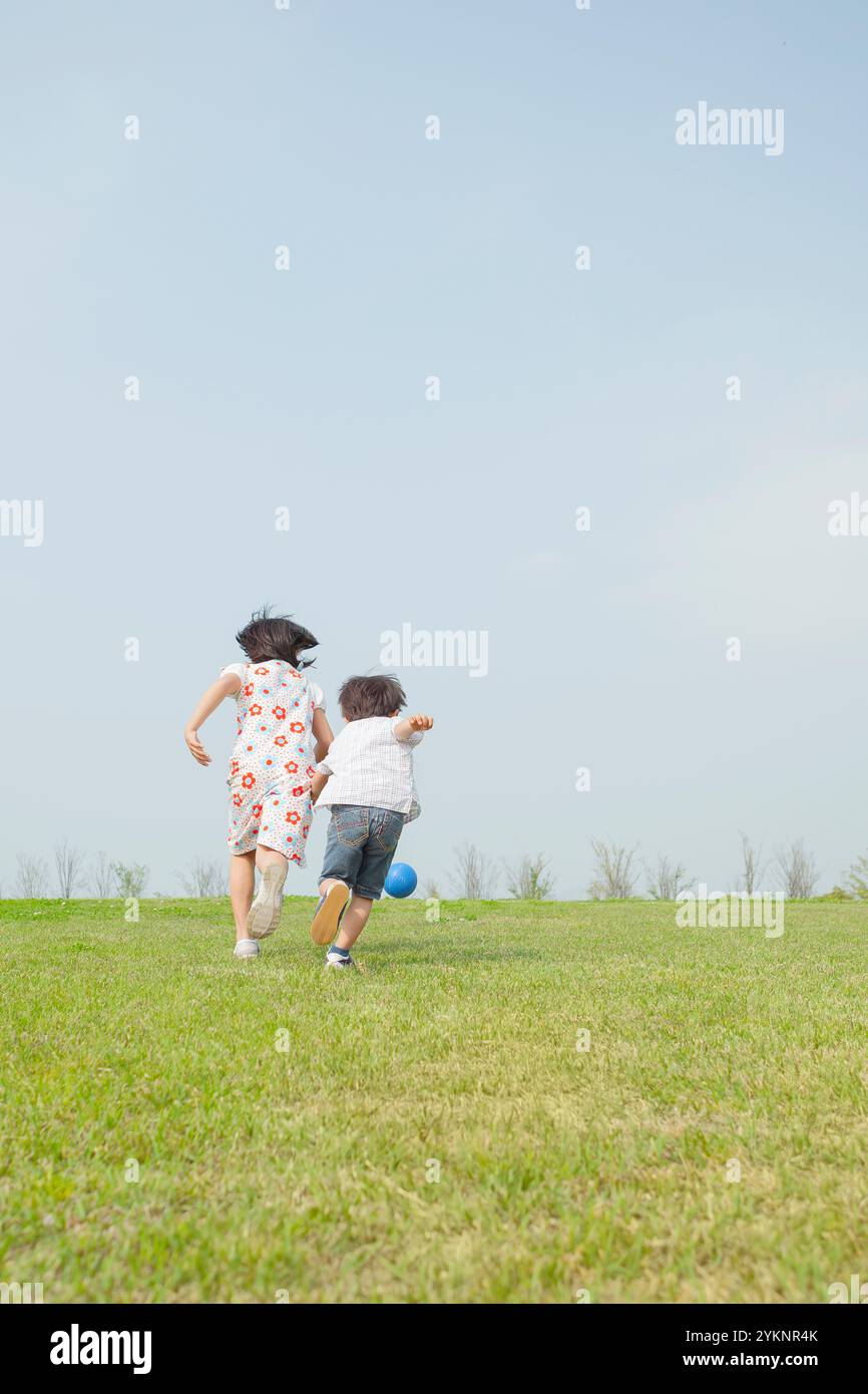 Sister and brother chasing ball Stock Photo - Alamy