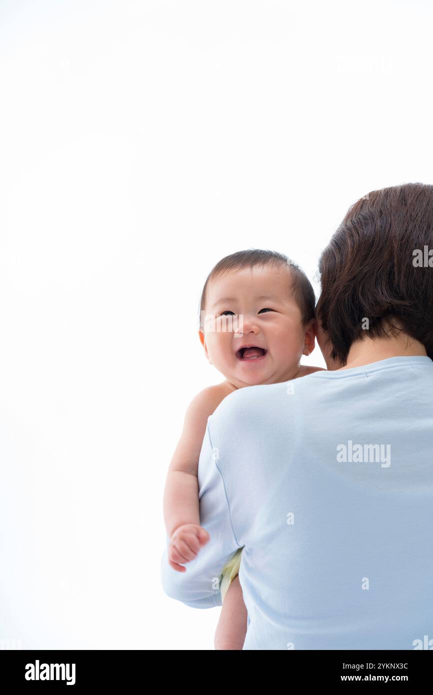Baby smiling from over mum's shoulder Stock Photo - Alamy