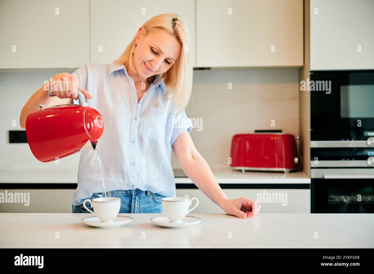 Young woman making morning coffee. Pretty female filling cup with hot ...