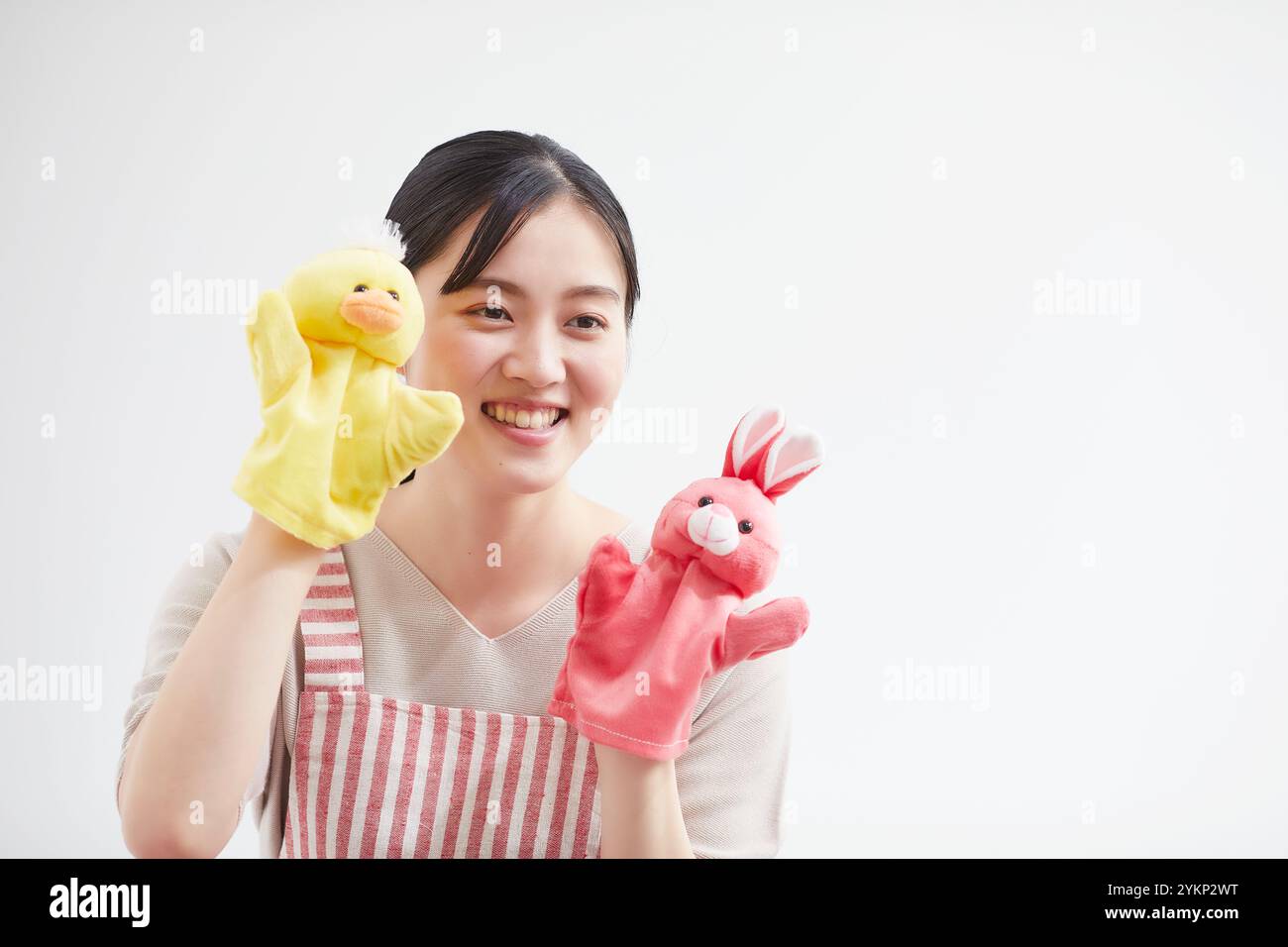 Young woman in apron holding puppet and feeding child Stock Photo - Alamy