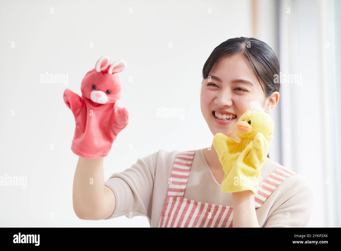 Young woman in apron holding puppet and feeding child Stock Photo - Alamy