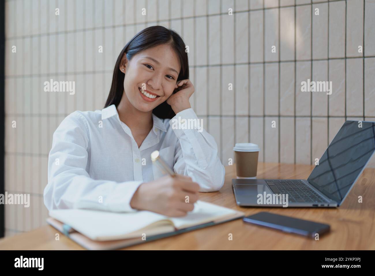 A young woman is happily engaged in her work, using a laptop and ...
