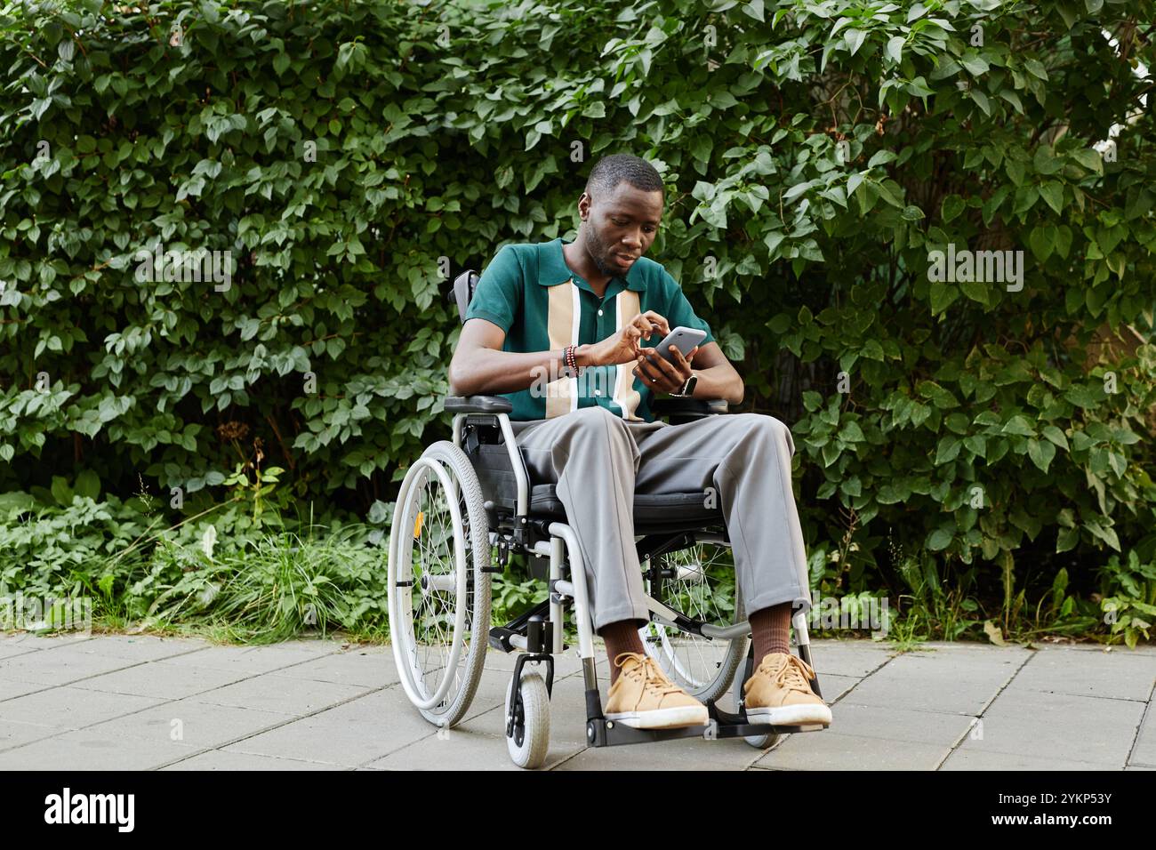 Full length portrait of adult man with disability using smartphone ...