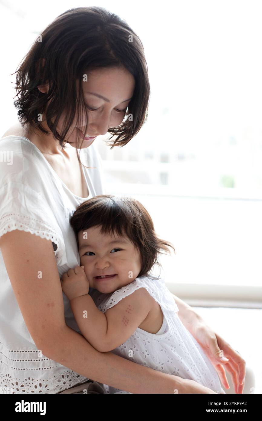 Smiling baby girl being pampered and carried by her mother Stock Photo ...