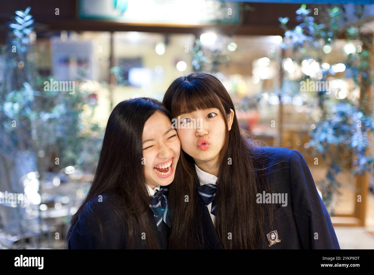 Two high school girls in front of a café after school, cheek to cheek ...