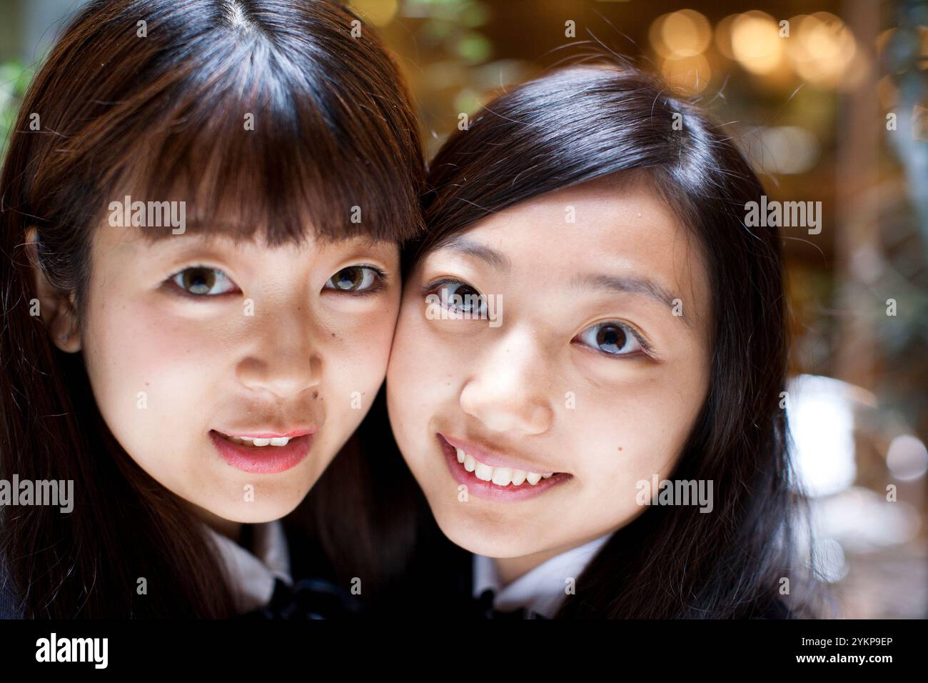 Two high school girls looking at each other cheek to cheek and smiling ...