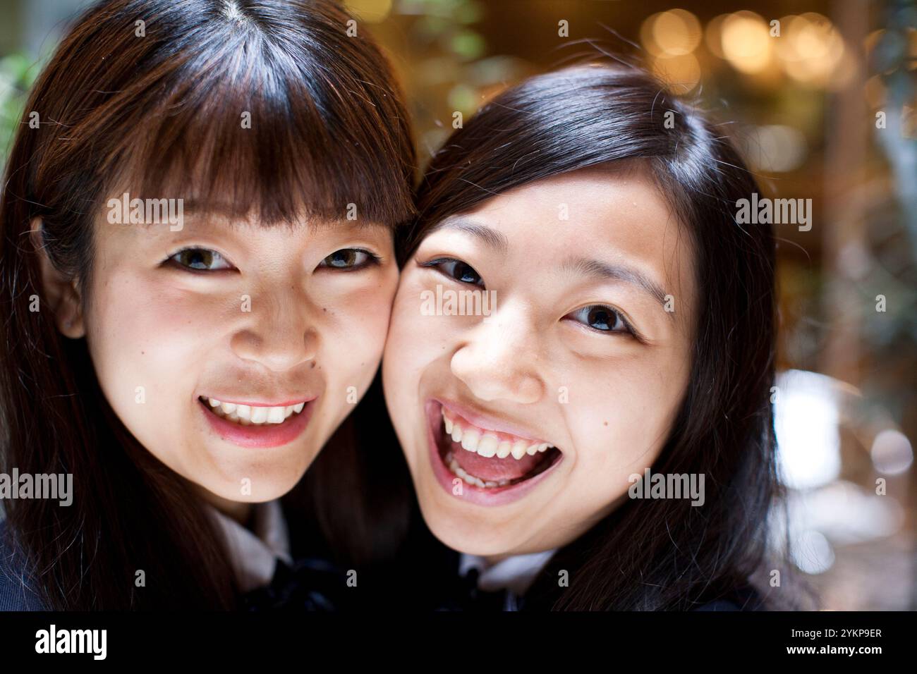 Two high school girls looking at each other with their cheeks pressed ...