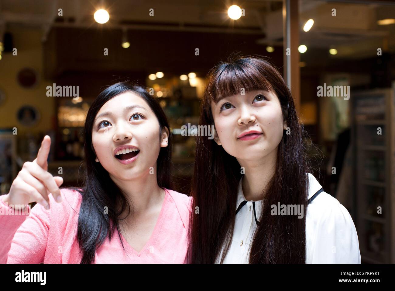 Two women looking up at the sky, pointing and staring at something ...