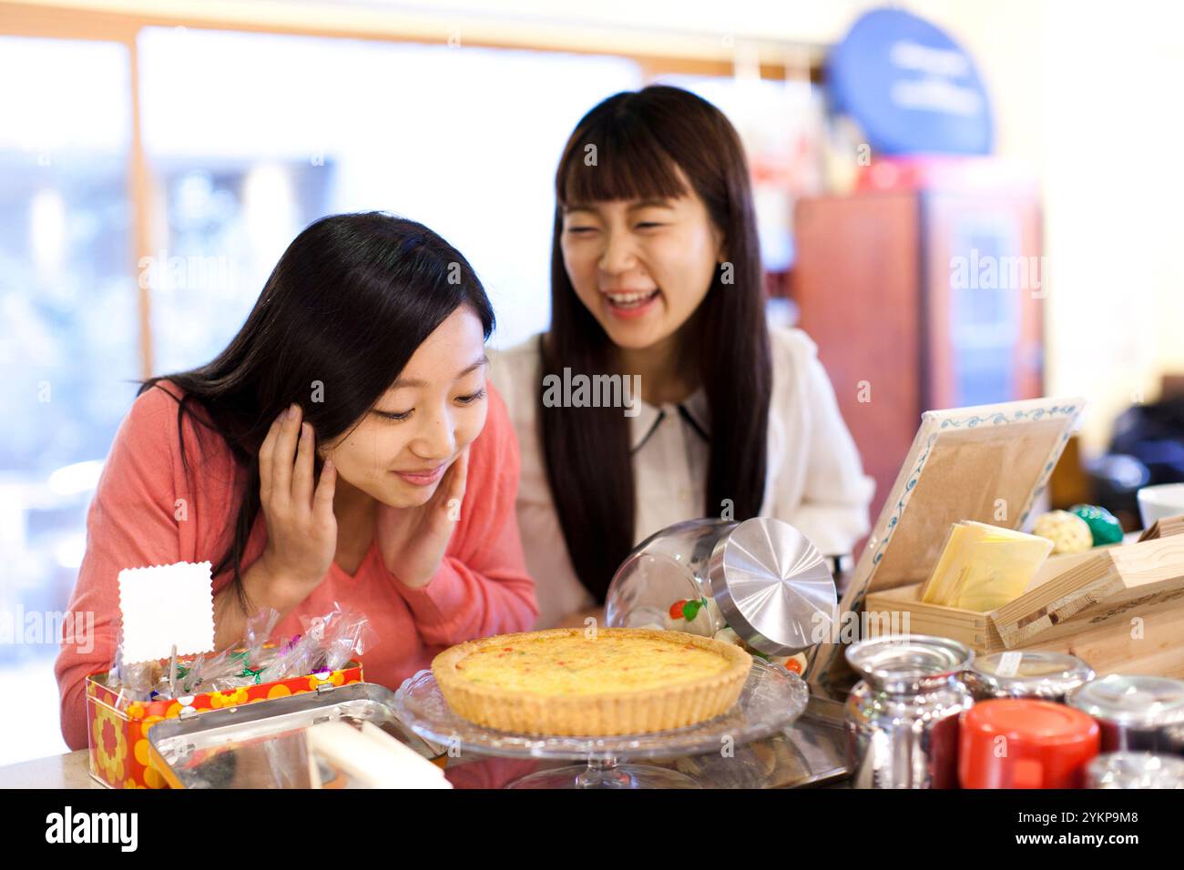 A woman smelling freshly made cakes at the counter of a café and her ...
