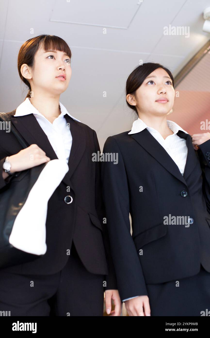 Two women in suits walking in office building Stock Photo - Alamy