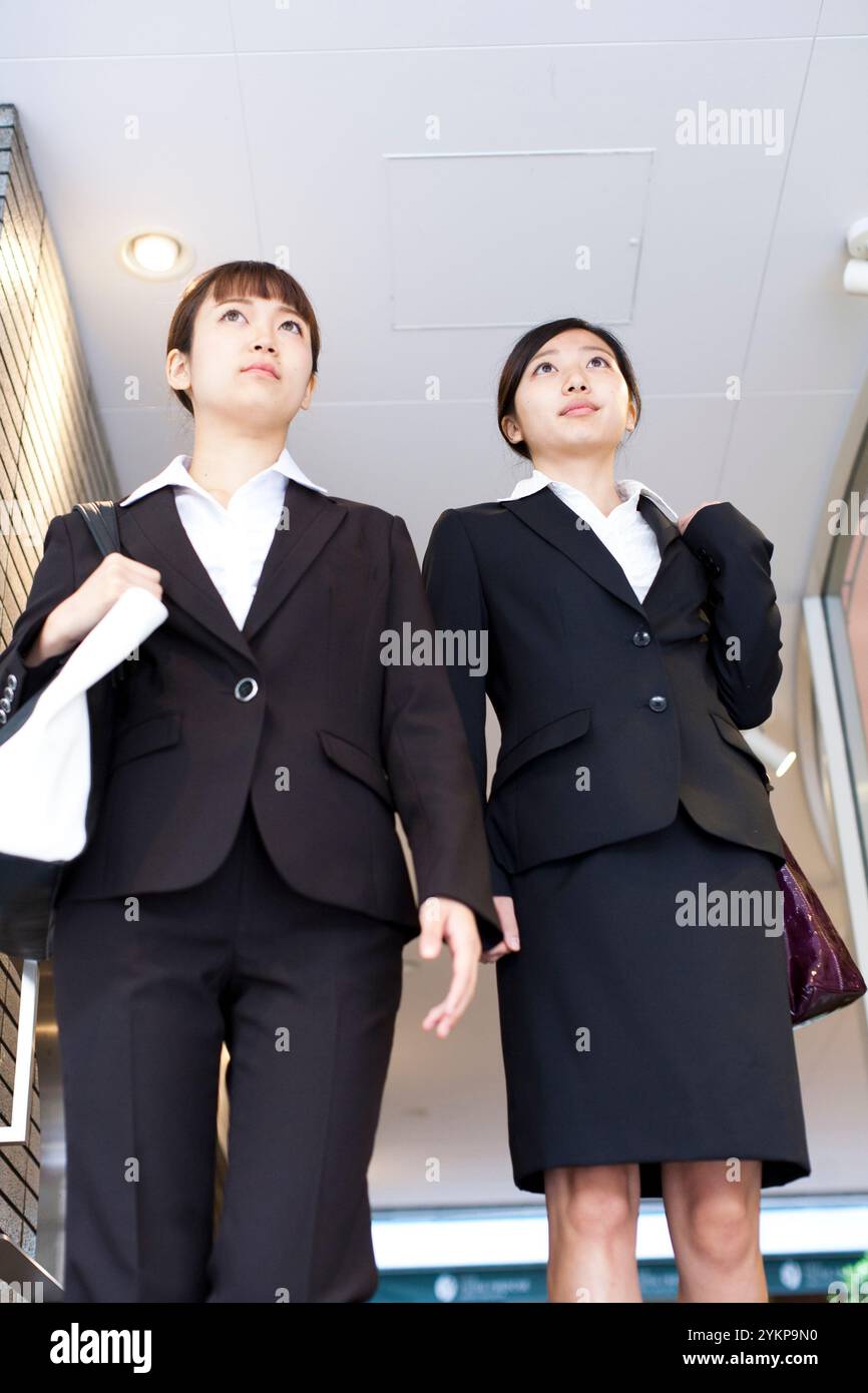 Two women in suits walking in office building Stock Photo - Alamy