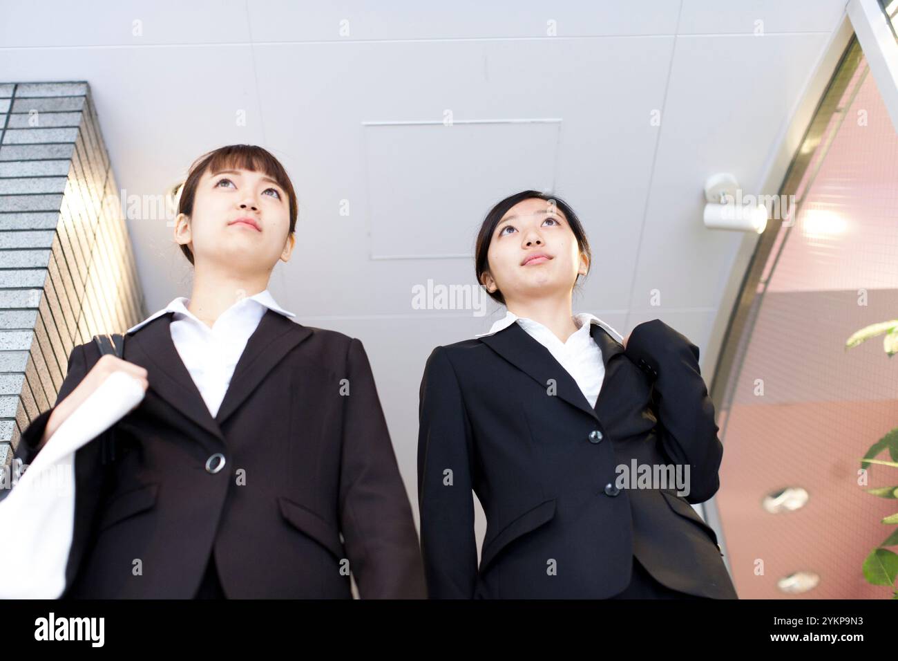 Two women in suits walking in office building Stock Photo - Alamy