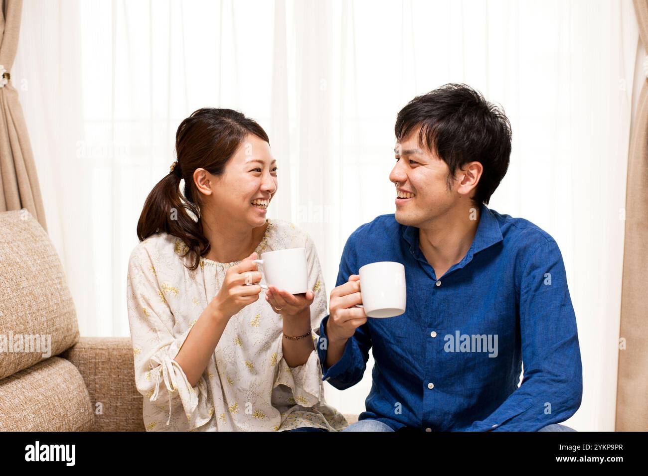 A friendly couple laughing over coffee in the living room Stock Photo ...