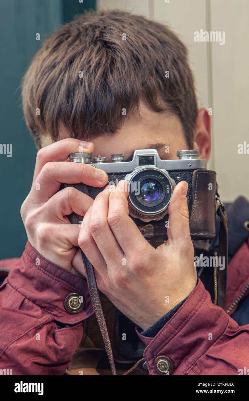 A young man takes pictures on a vintage camera. Film camera photography ...