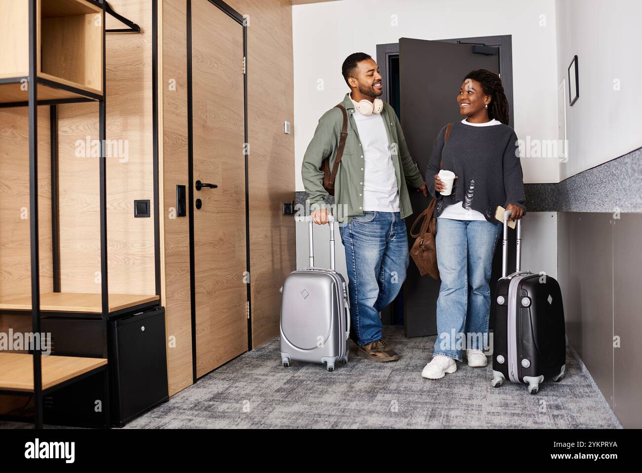A young couple smiles and connects while entering their cozy hotel room ...