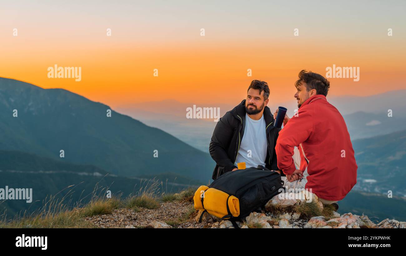 Two friends travelers taking a break at the top of the mountain during ...