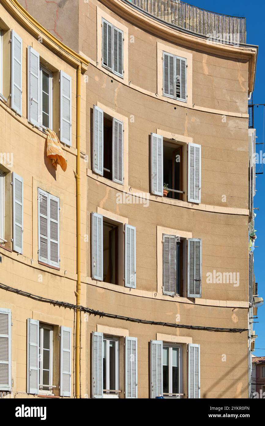 A curved building facade in Marseille with multiple shuttered windows ...