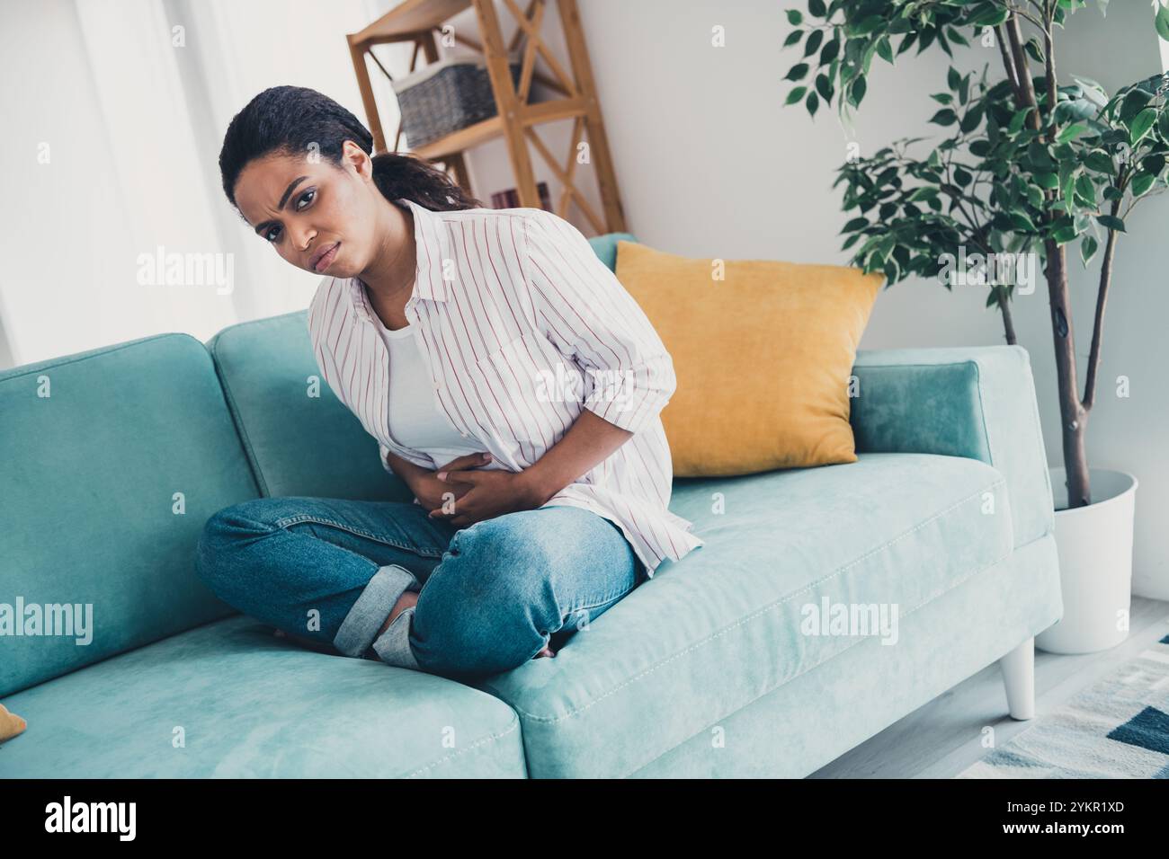 Full size photo of pretty young girl sit couch touch hurt belly wear ...