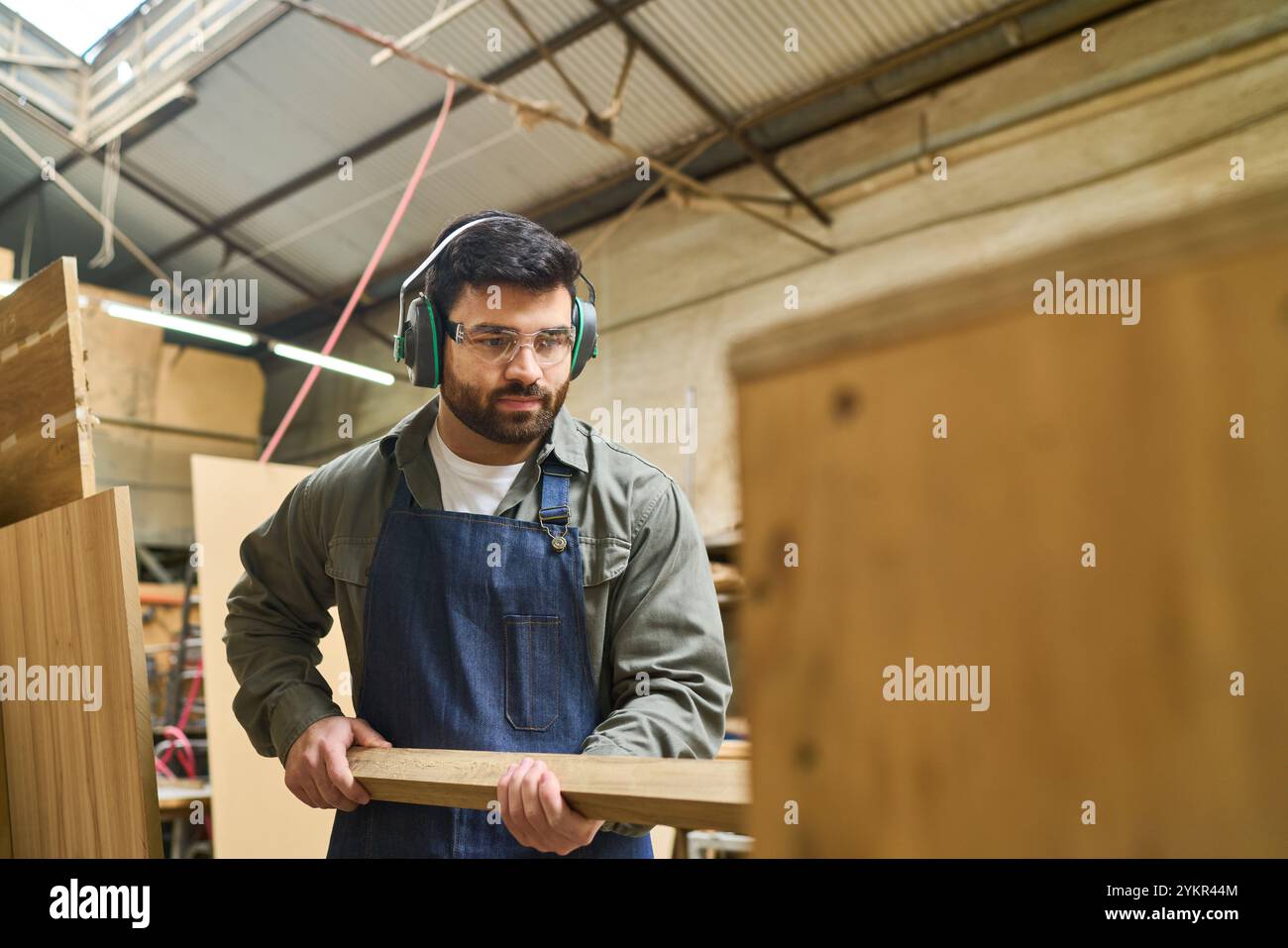 A dedicated worker in safety gear concentrates on handling wood ...