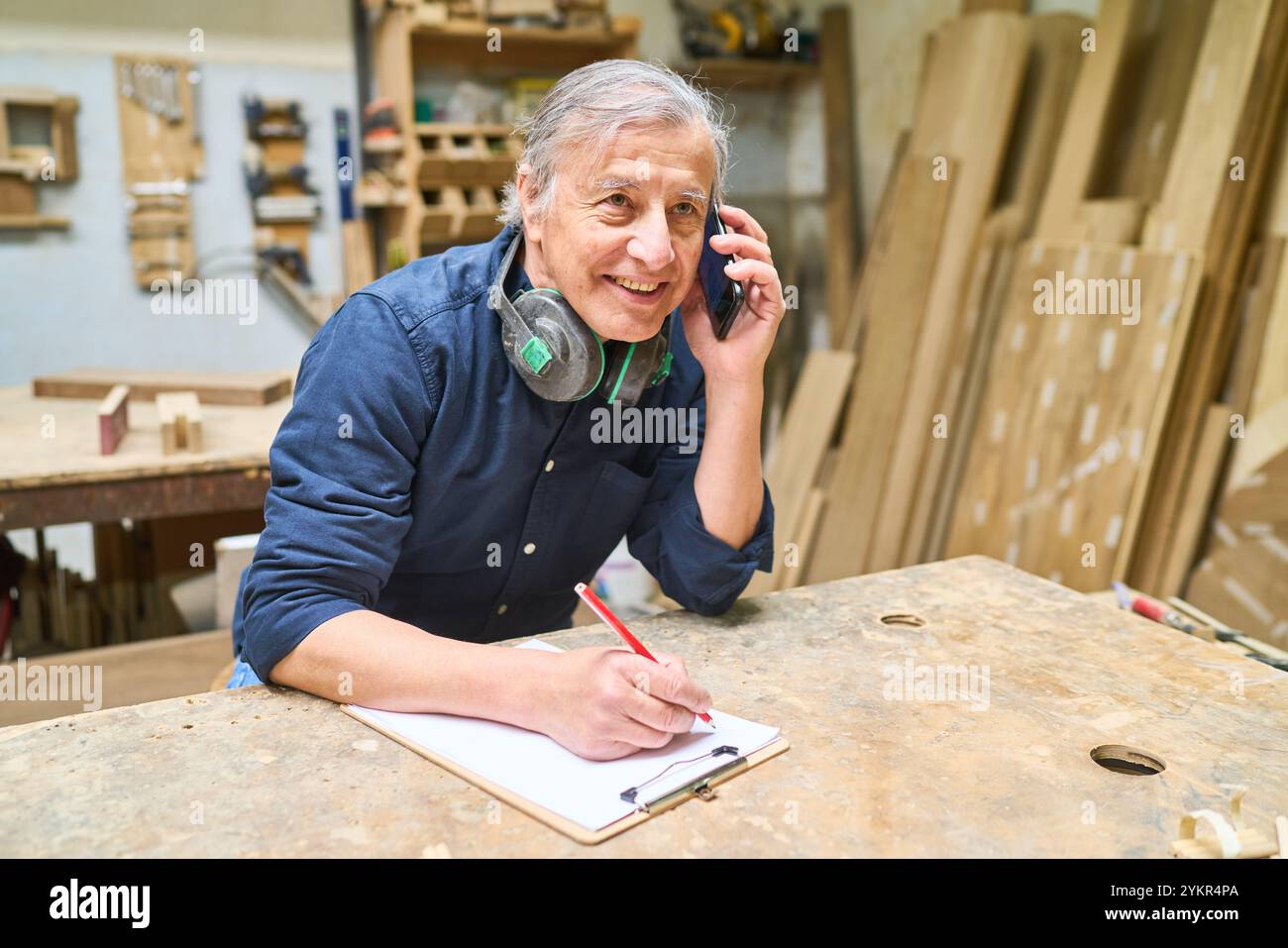 A seasoned professional with safety earmuffs talks on a phone while ...