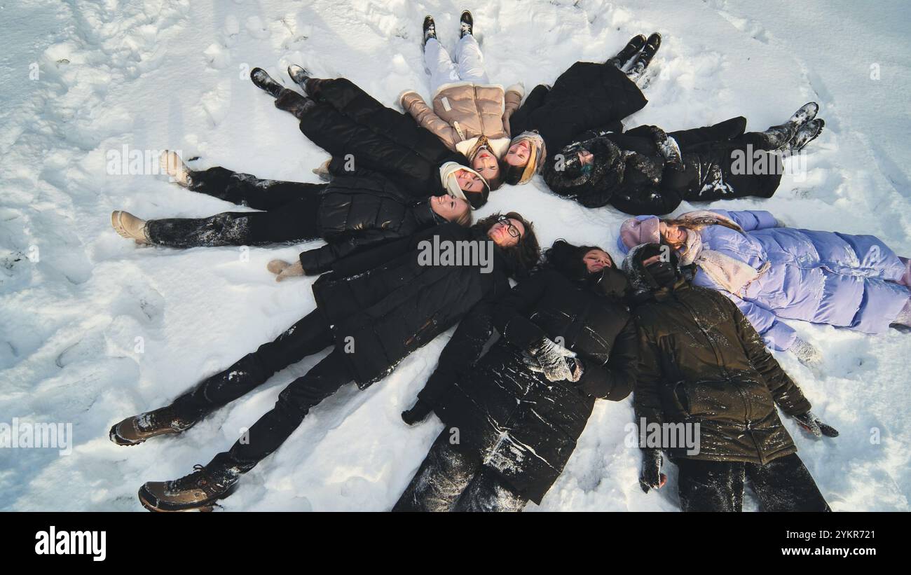 Schoolgirls having fun in the snow, forming a star shape with their ...