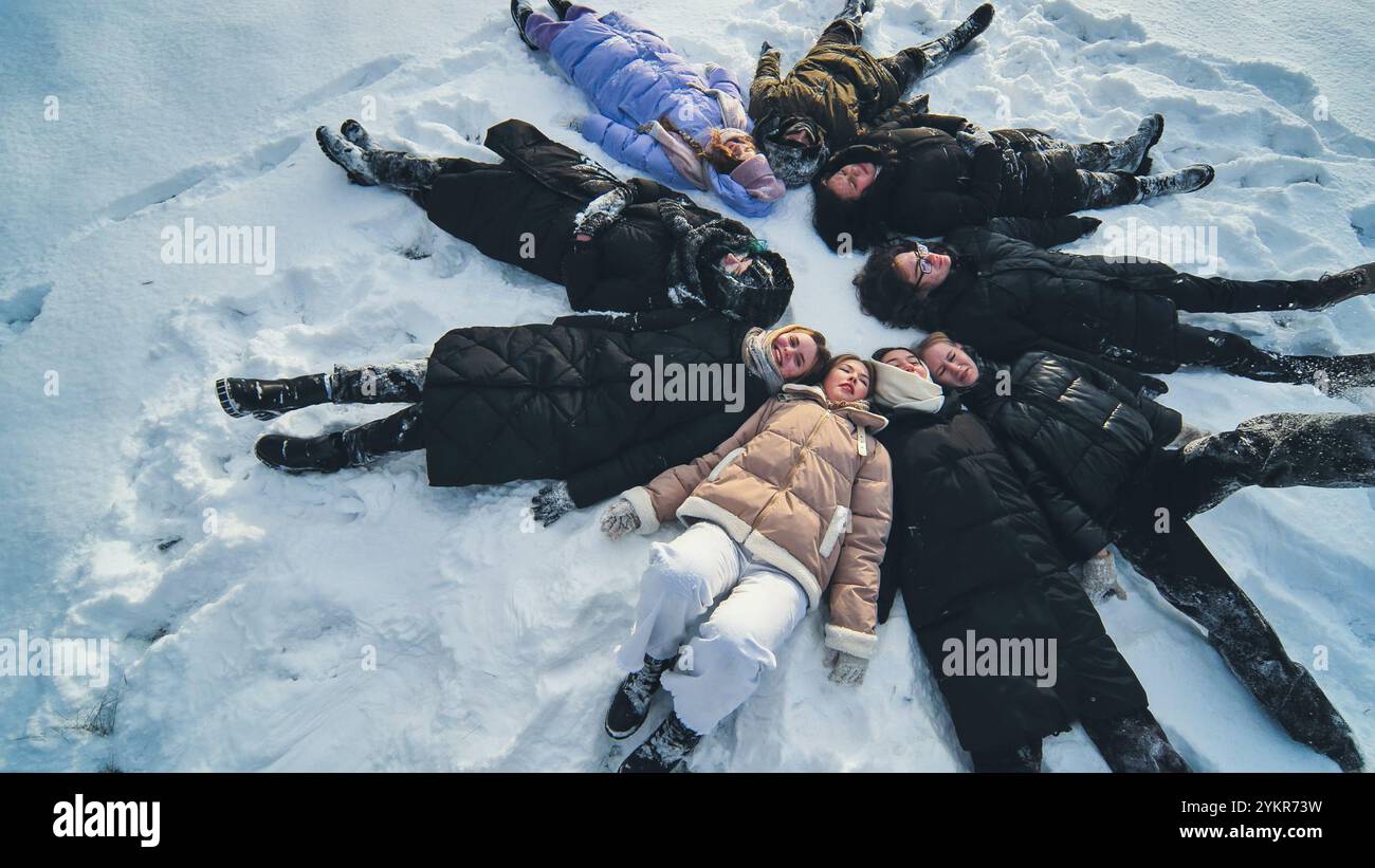 Group of schoolgirls making snow angels, lying on fresh snow during a ...
