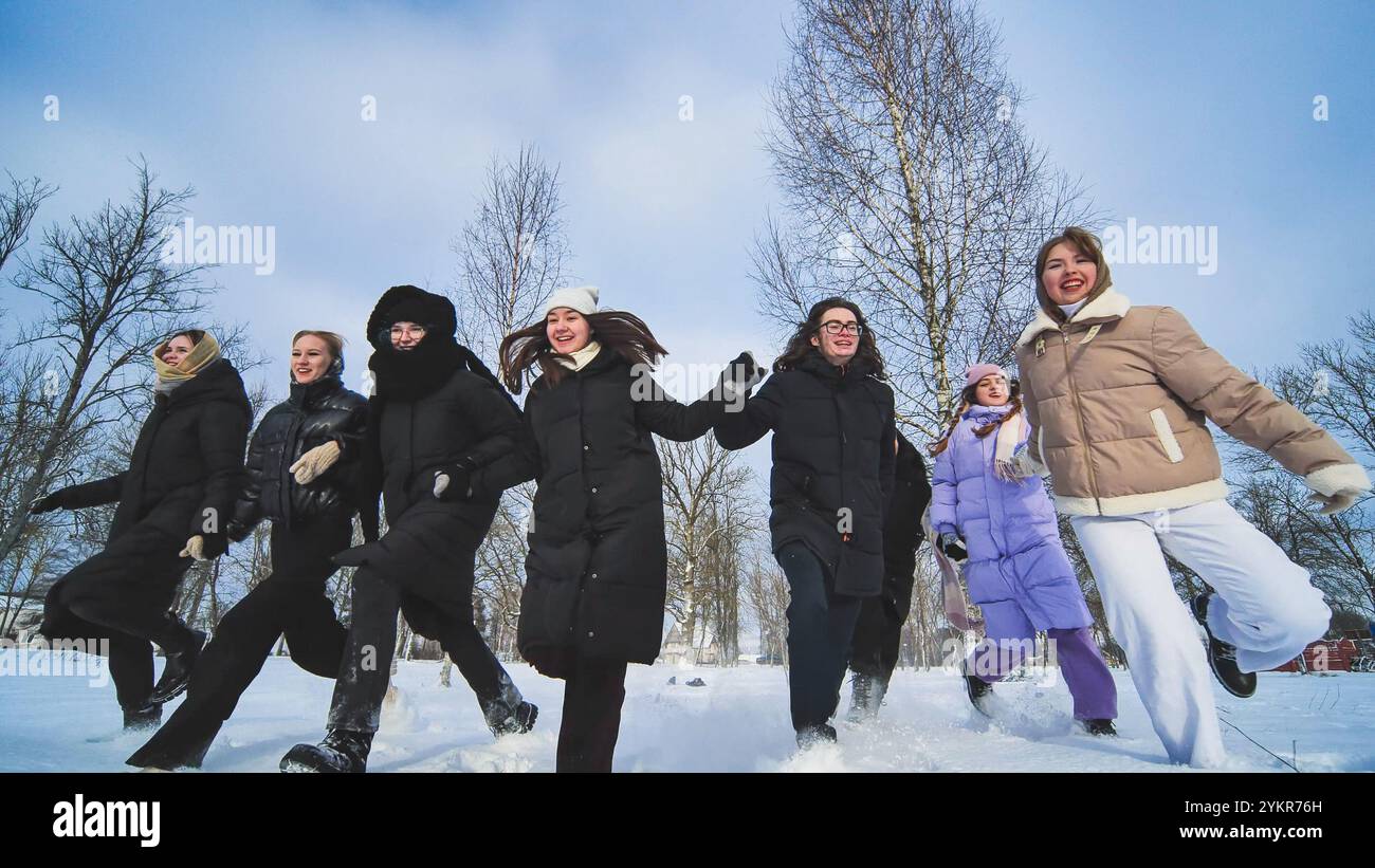 Schoolgirls happily skipping through a snowy park, delighting in winter ...