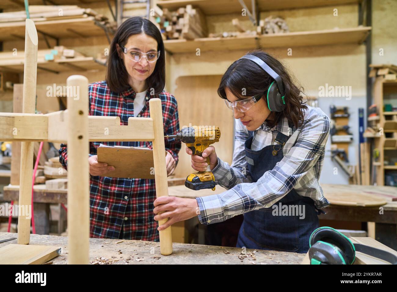 Two people collaborate in a lumberyard, focusing on woodworking skills ...