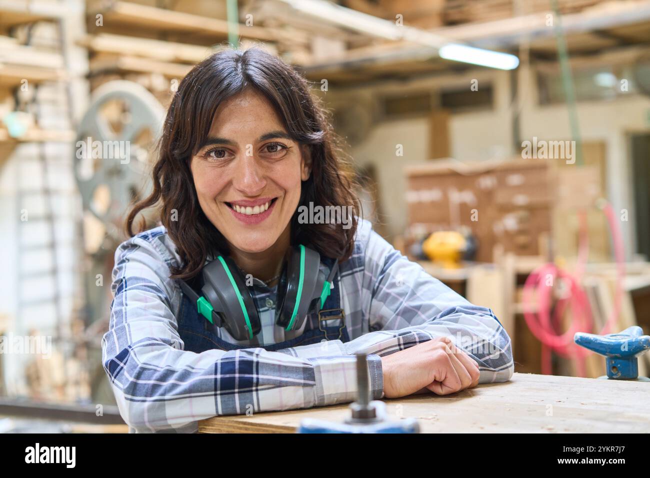 A confident young woman smiles while working in a busy lumberyard ...