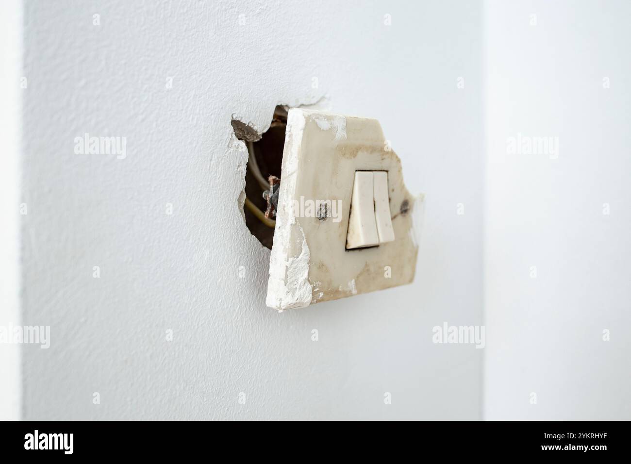 Broken plastic light switch ripped from a white wall, abstract backdrop ...