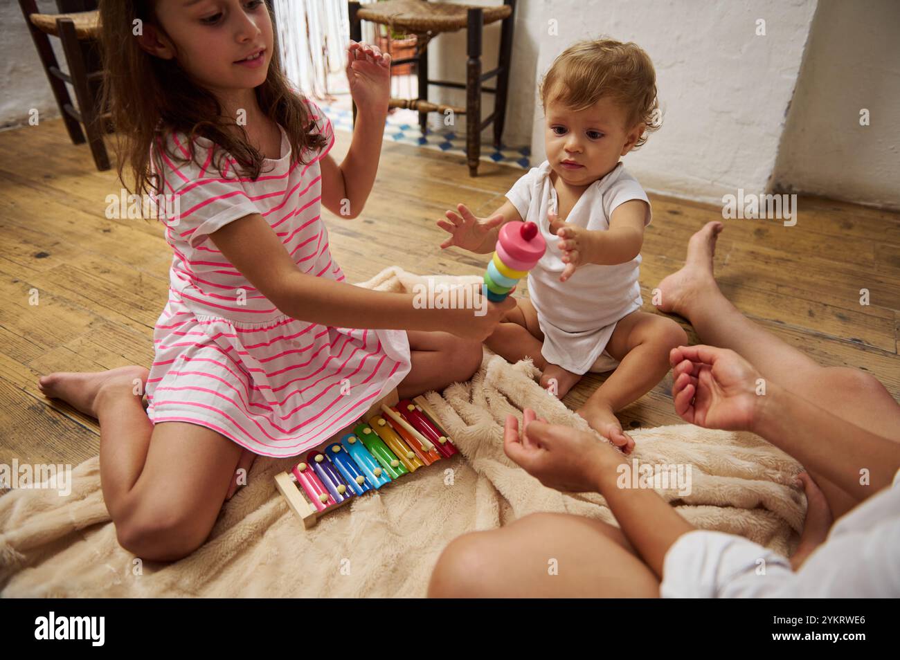 Two siblings enjoy playtime with colorful musical toys on a soft ...