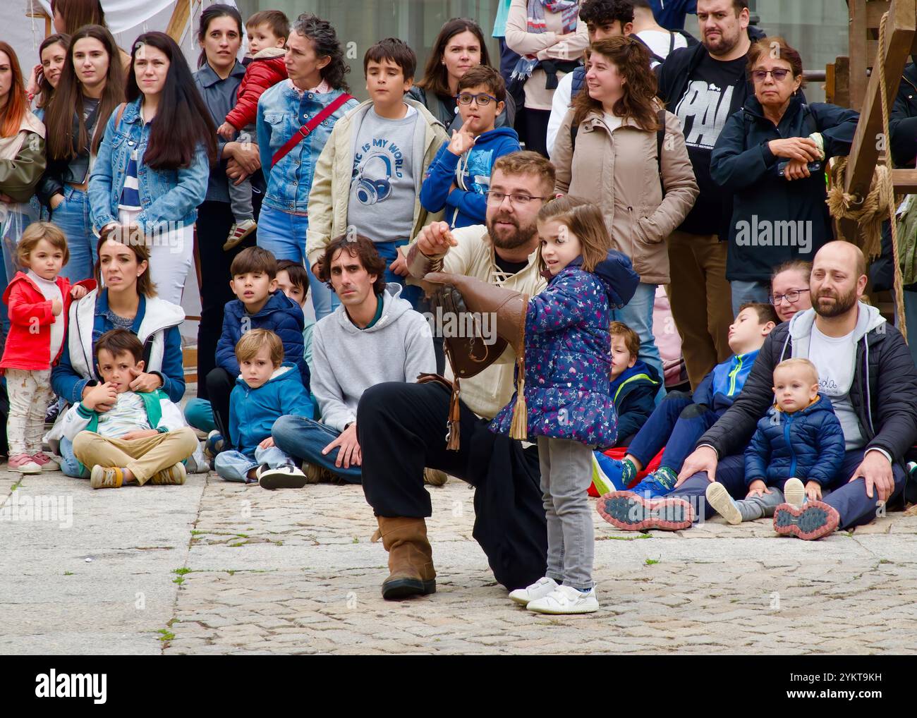 Crowd watching a bird handler in costume and young girl waiting to ...