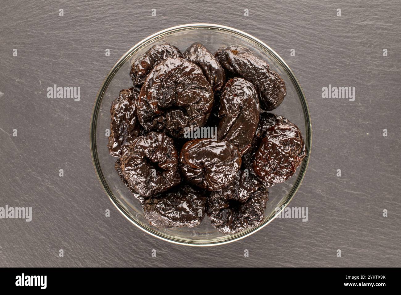 Sweet prunes in a ceramic plate on a slate stone, macro, top view Stock ...