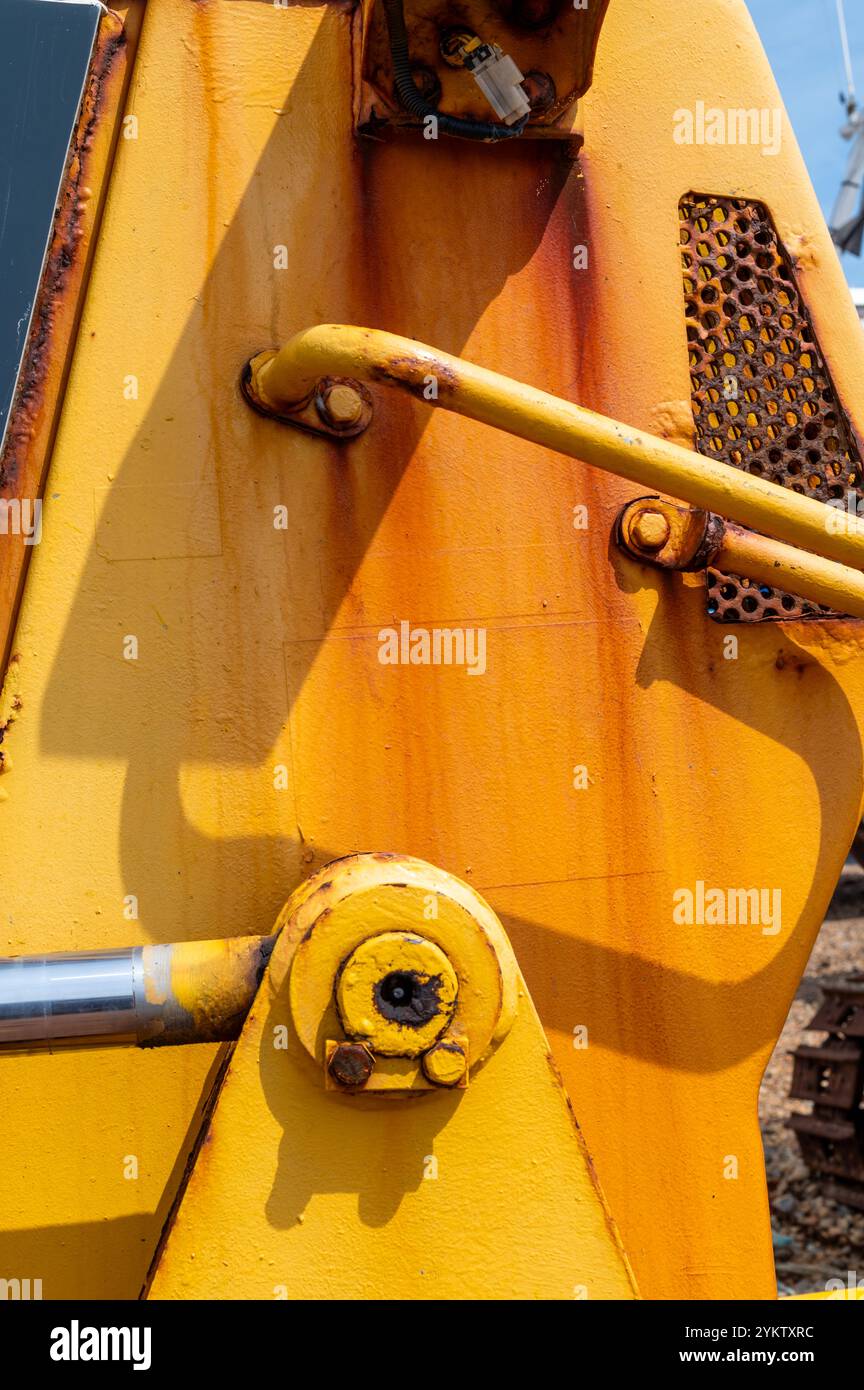 Hydraulic arm on the side of a rust-streaked bright yellow bulldozer on ...