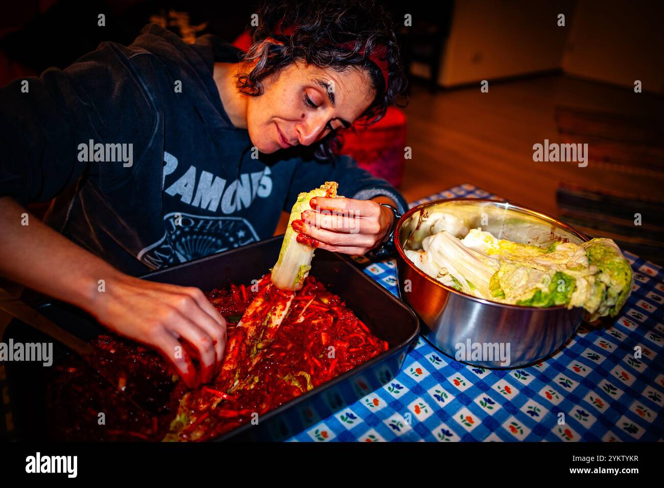 A woman is seen soaking each cabbage leaf in the kimchi paste. Kimchi ...